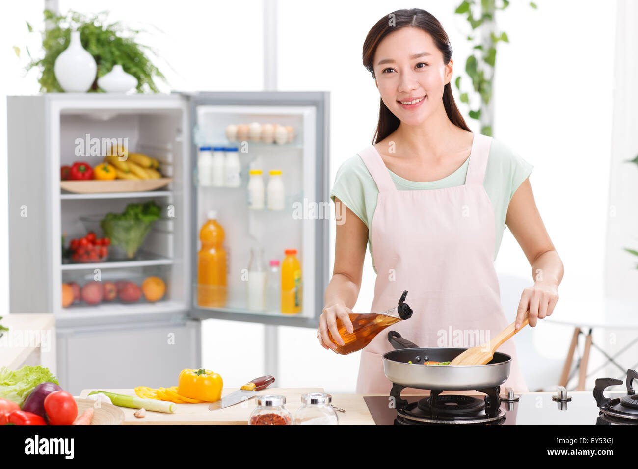 Portrait of young woman cooking in kitchen Stock Photo - Alamy