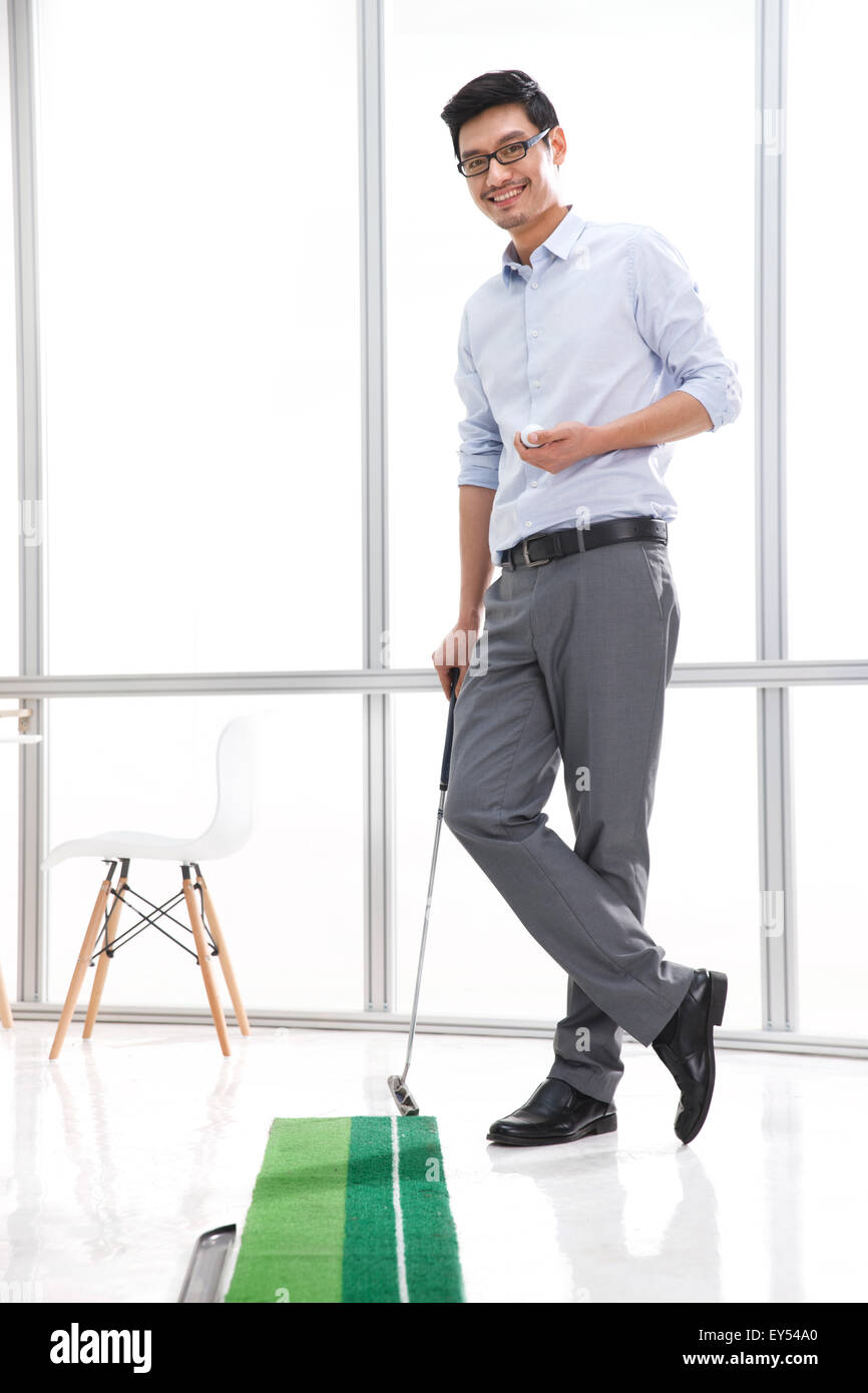 Portrait of businessman playing golf in office Stock Photo - Alamy