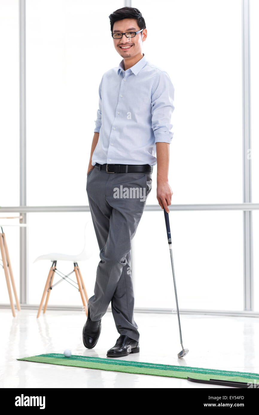Portrait of businessman playing golf in office Stock Photo - Alamy