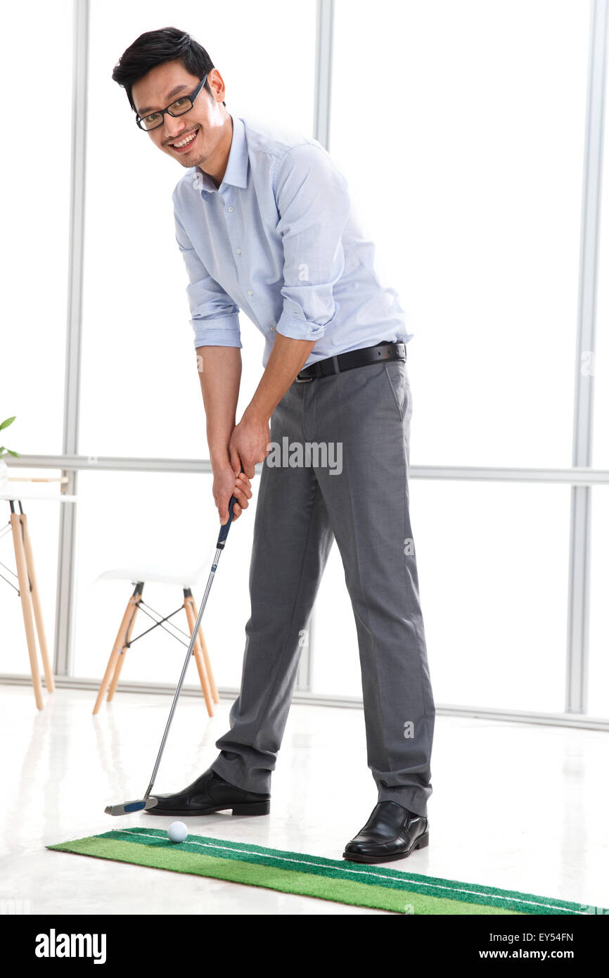 Portrait of businessman playing golf in office Stock Photo - Alamy
