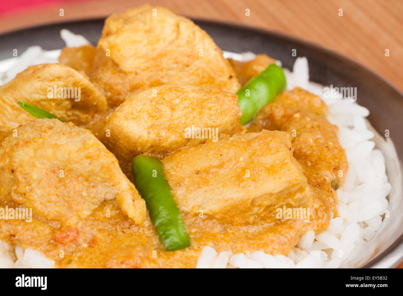 Indian chicken curry served on rice in authentic copper utensil. Green ...