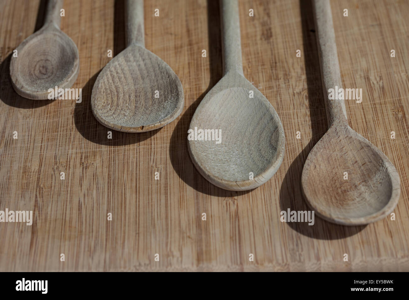 Four wooden spoons placed on a bamboo board at different lengths Stock ...