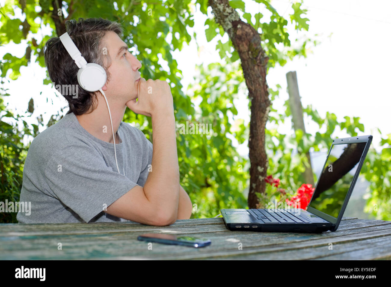 man sitting outdoor working with a laptop Stock Photo - Alamy
