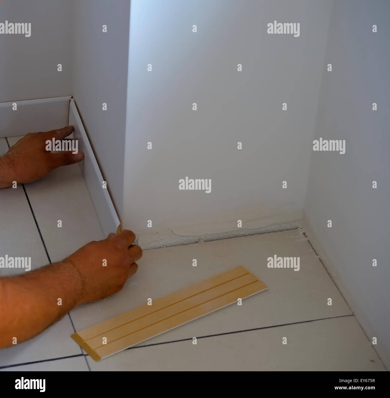 Carpenter on work putting wood skirting board with glue. Caulking Gun ...