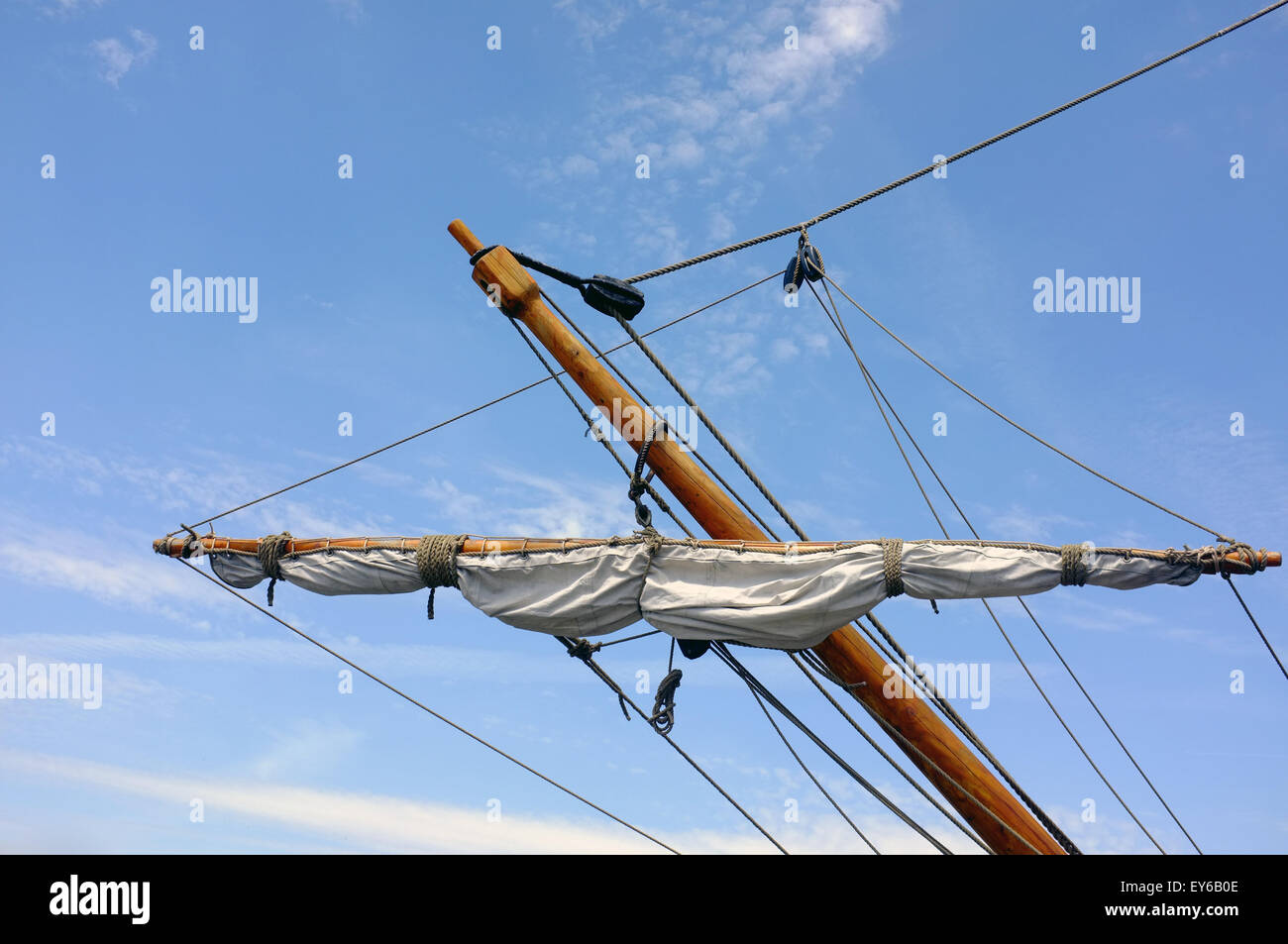 A furled sail on the front mast of a sailing ship set against a blue ...