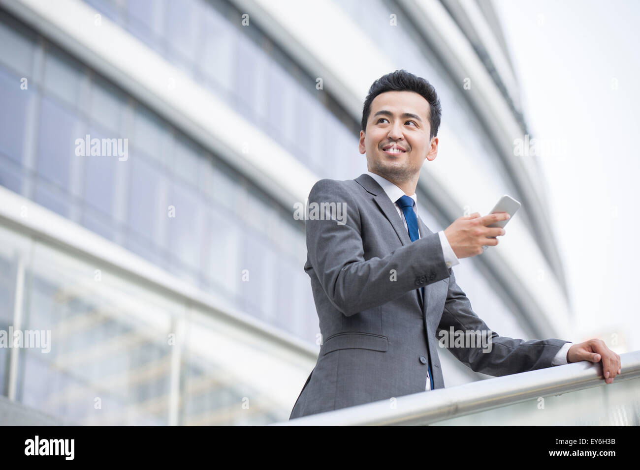 Businessman standing in front of office building Stock Photo - Alamy