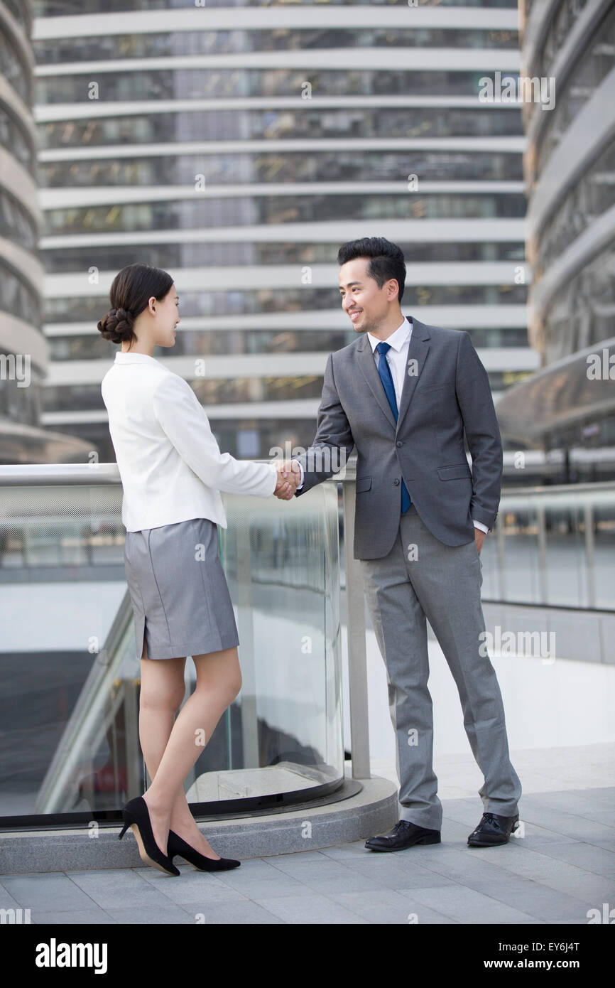 Standing leaning smiling building exterior communication shaking hands ...