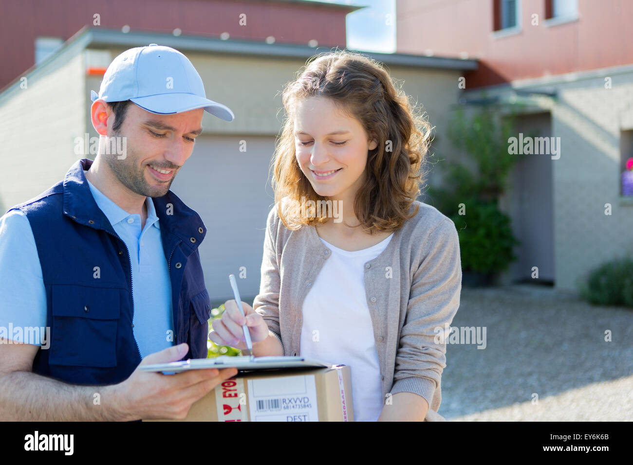 View of a Young attractive woman signing on delivery paper Stock Photo ...