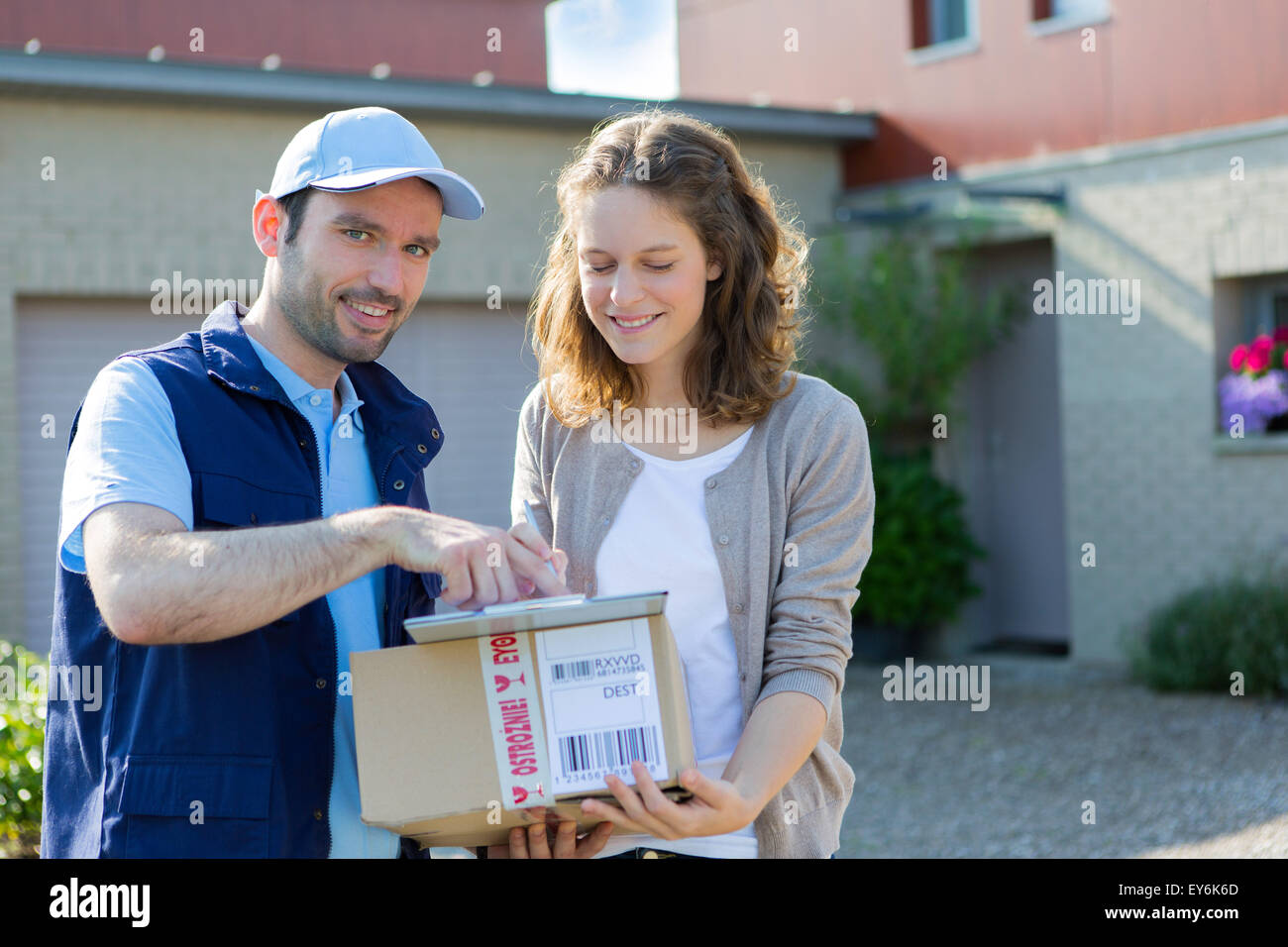 View of a Young attractive woman signing on delivery paper Stock Photo ...