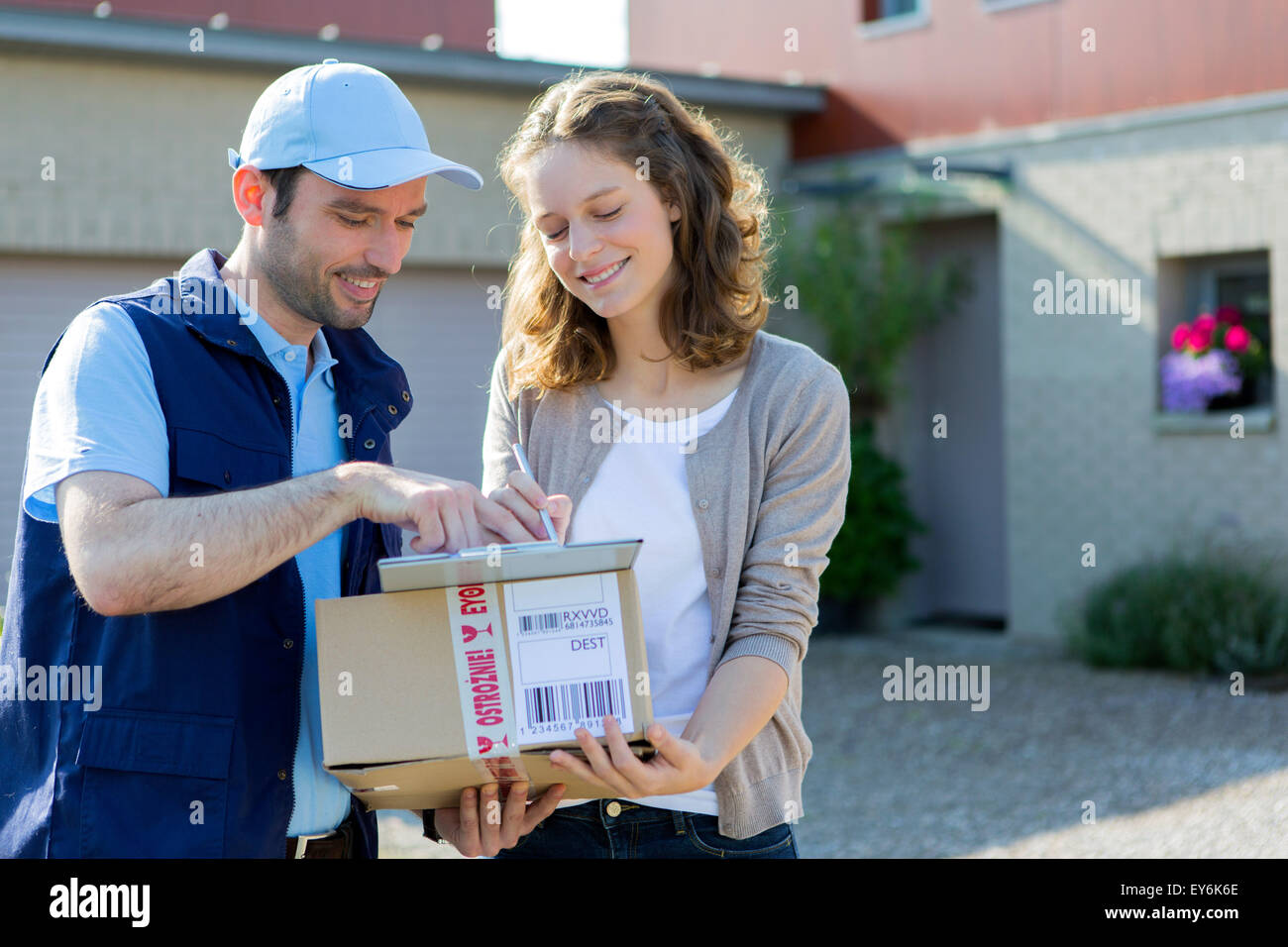 View of a Young attractive woman signing on delivery paper Stock Photo ...