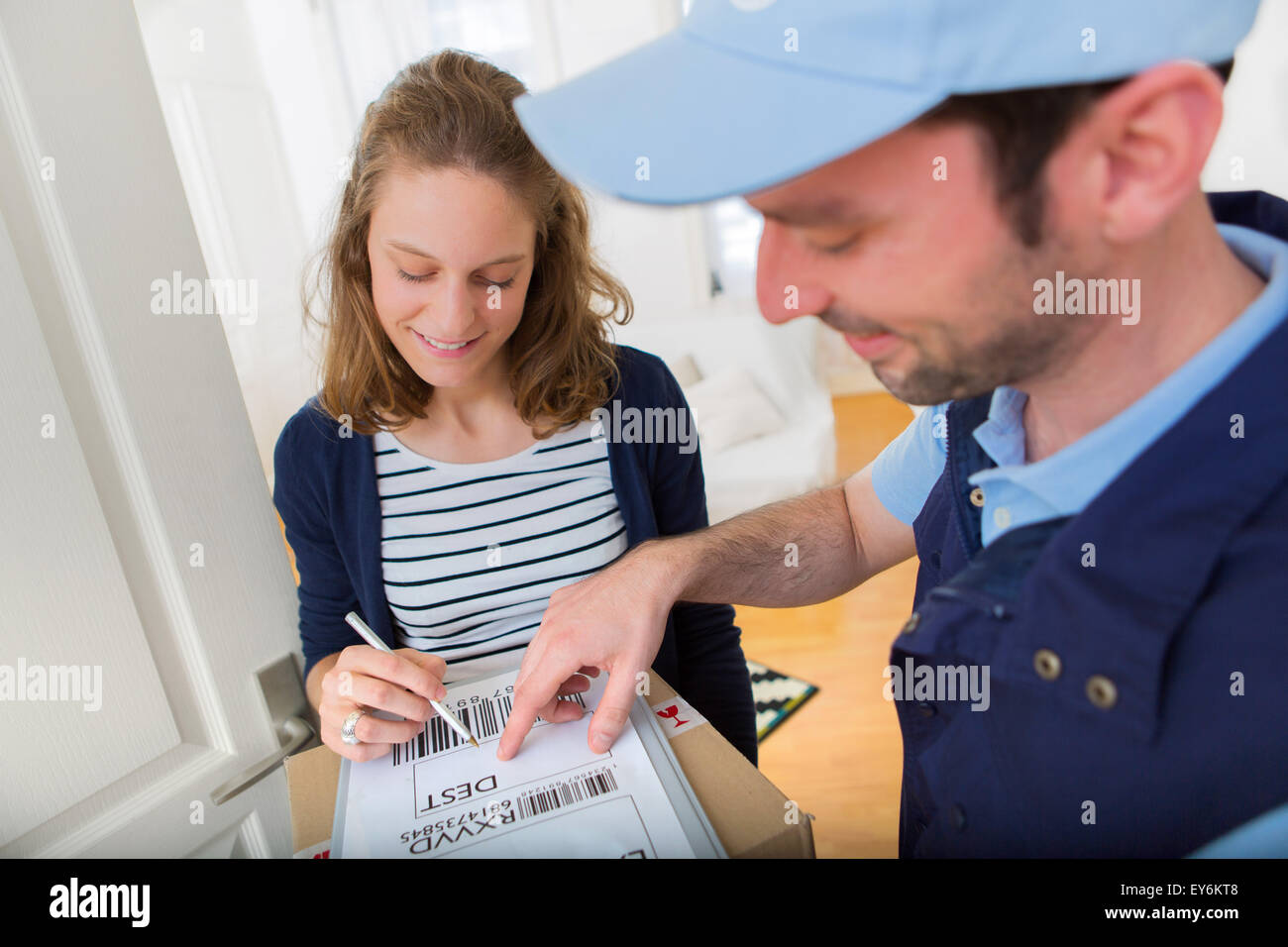View of a Young attractive woman signing on delivery paper Stock Photo ...