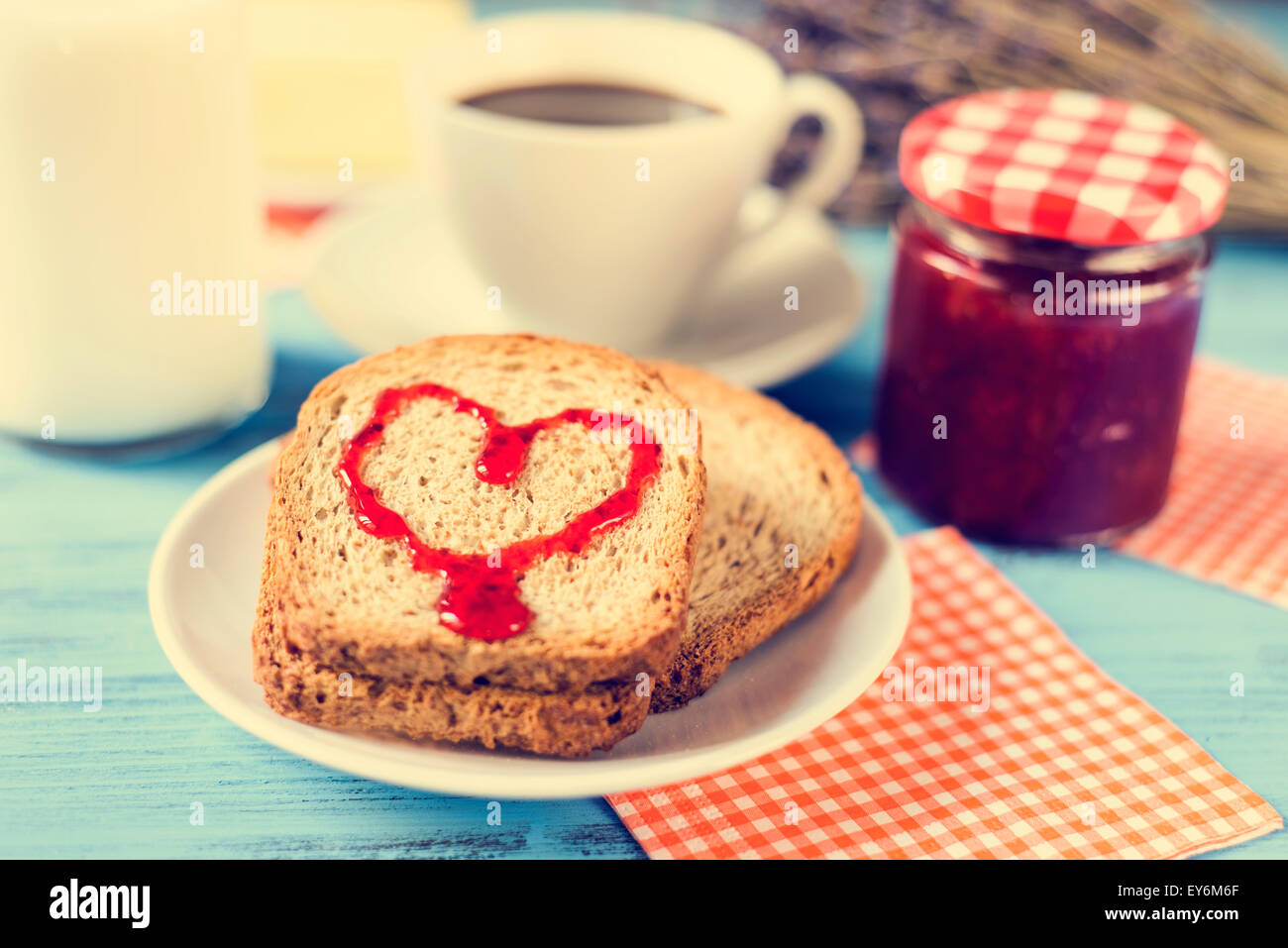 jam forming a heart on a toast, on a rustic blue wooden table, with a ...