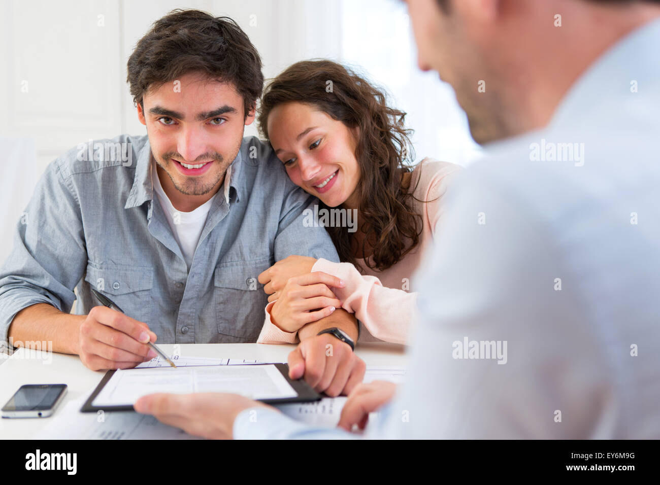 View of a Young attractive couple signing contract Stock Photo - Alamy