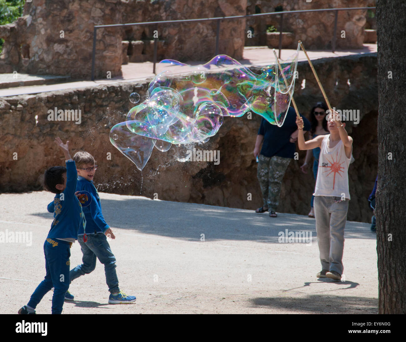Children chasing giant bubbles created by street performer in Parc ...