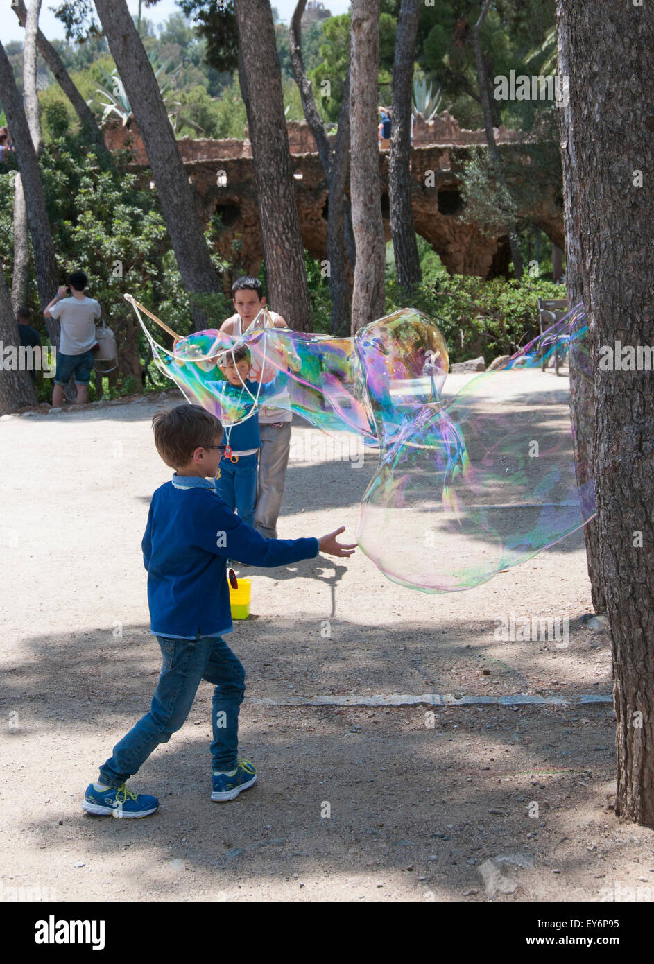 Child chasing giant bubbles created by street performer in Parc Guell ...