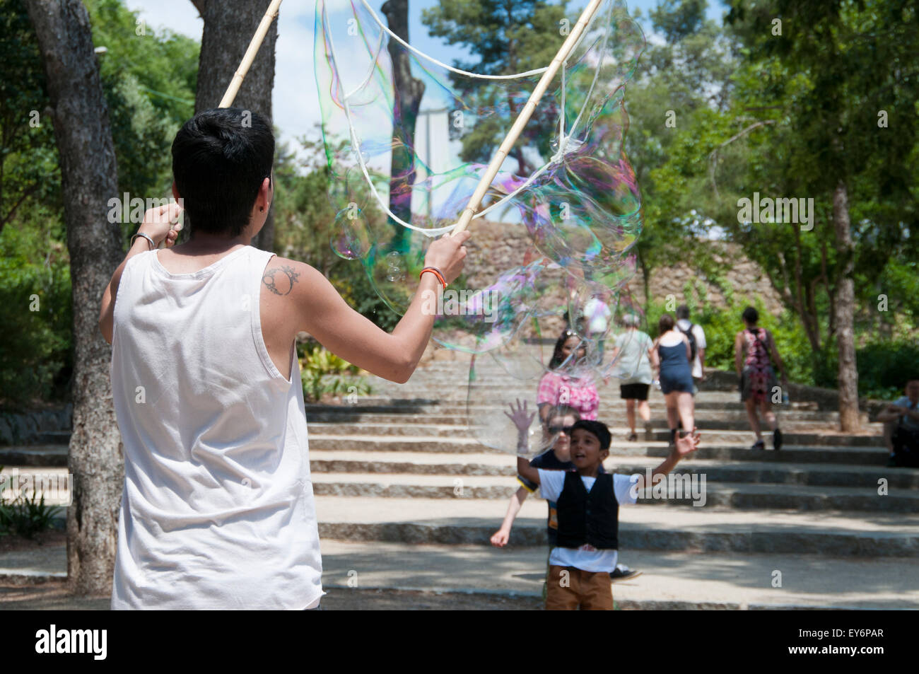 Child chasing giant bubbles created by street performer in Parc Guell ...