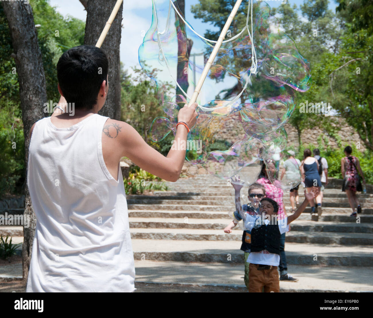 Child chasing giant bubbles created by street performer in Parc Guell ...