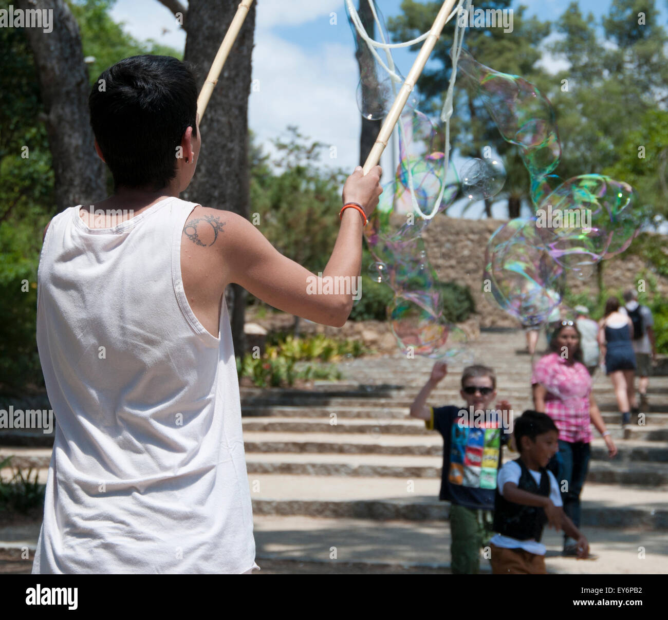 Child chasing giant bubbles created by street performer in Parc Guell ...