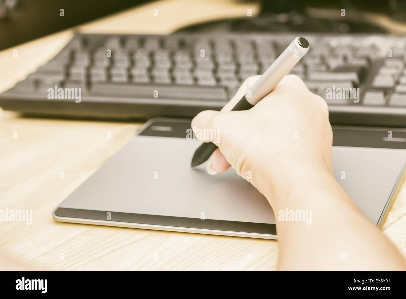 Retro image of female hand of a designer drawing with the stylus on a ...