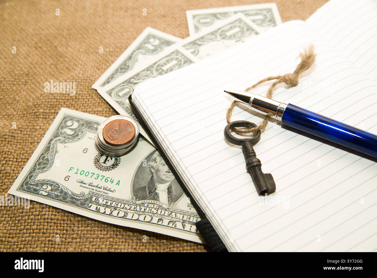 Opened notebook with a blank sheet, pen, key and money on the old ...