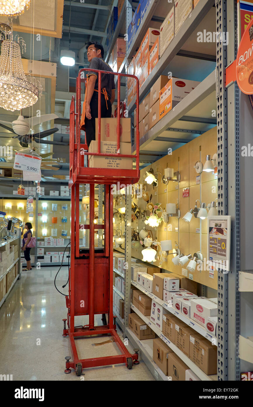 Shelf stacking. Loading hoist and operator. Department store. Thailand ...