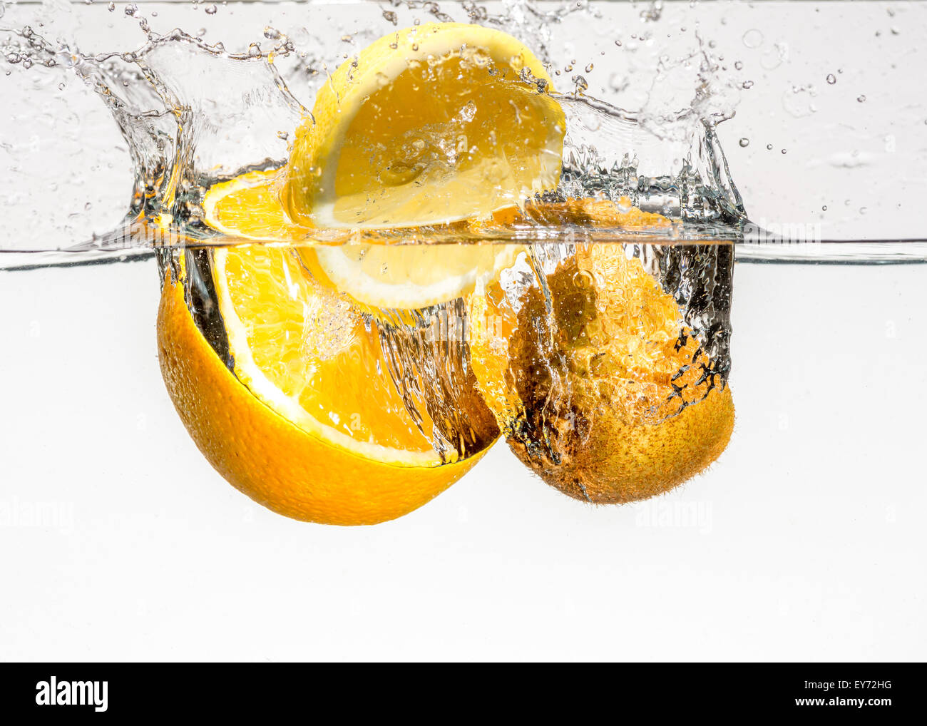 Fruit splash. Lemon, orange and kiwi fruit halves splashing into clear ...