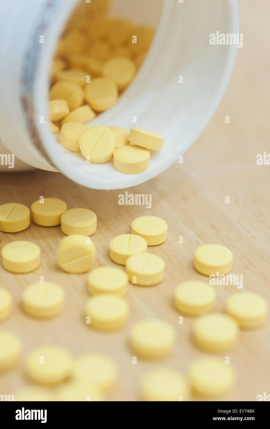 Medicine spilling out of a bottle on wood table Stock Photo - Alamy