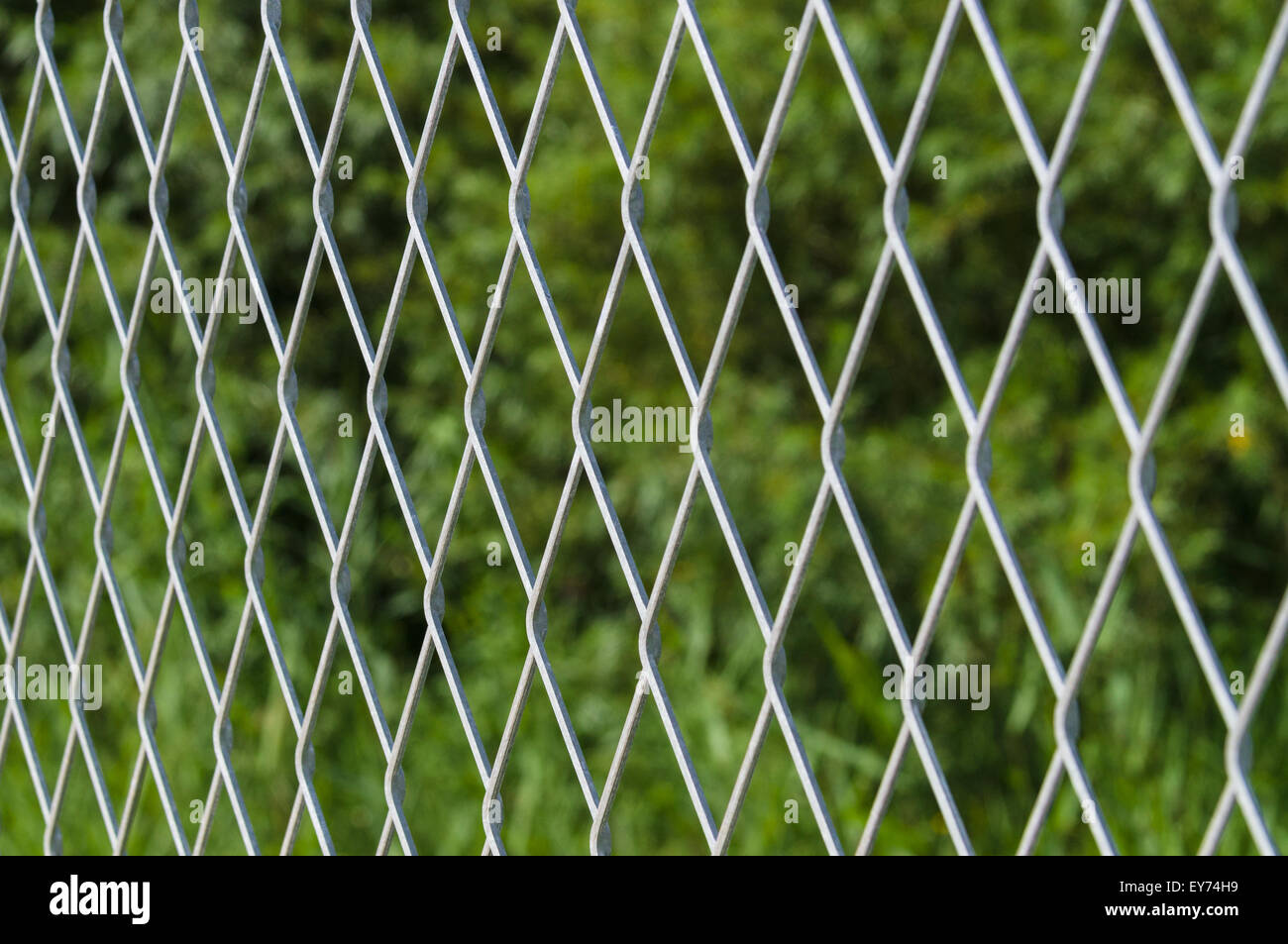 Blurred metallic mesh fence against green background Stock Photo - Alamy