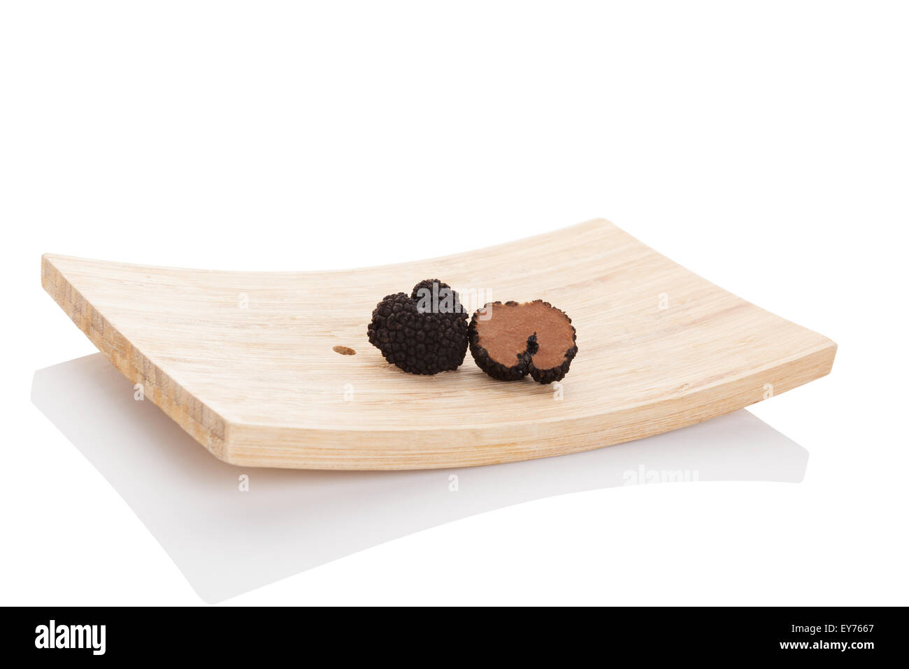 Truffles, rare mushrooms. Cut truffles on wooden plate isolated on ...