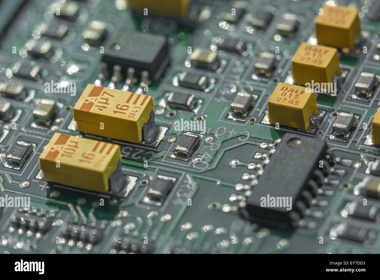 Macro-photo of printed circuit board (PCB) showing yellow tantalum (a ...