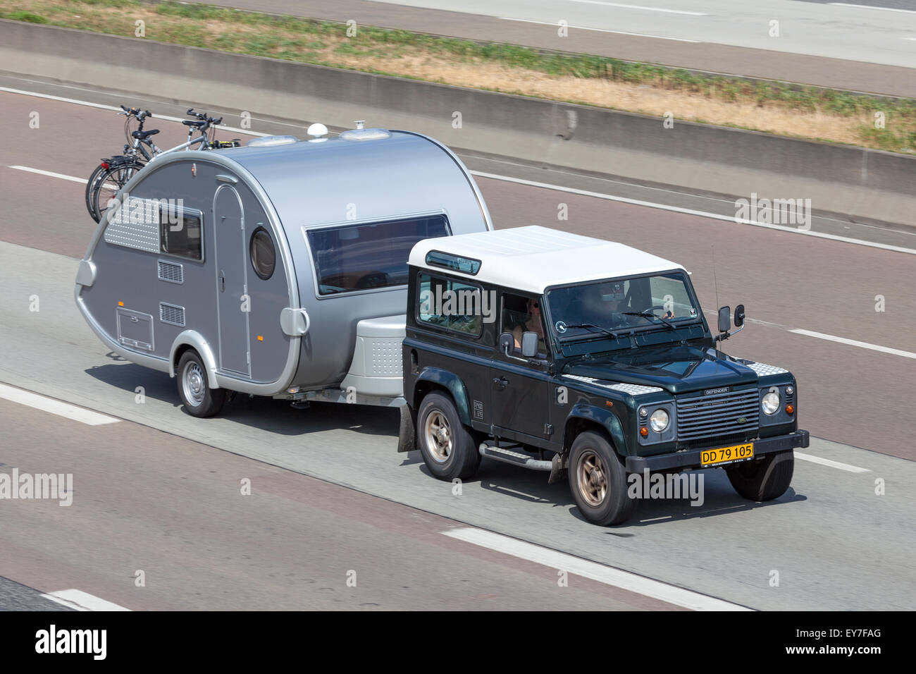 Land Rover Defender with a small caravan travelling at the A5 highway ...