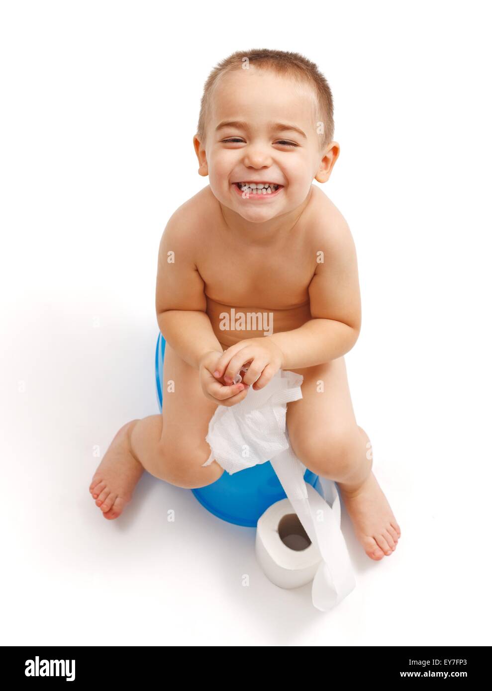 Laughing little boy sitting on potty and playing with toilet paper ...