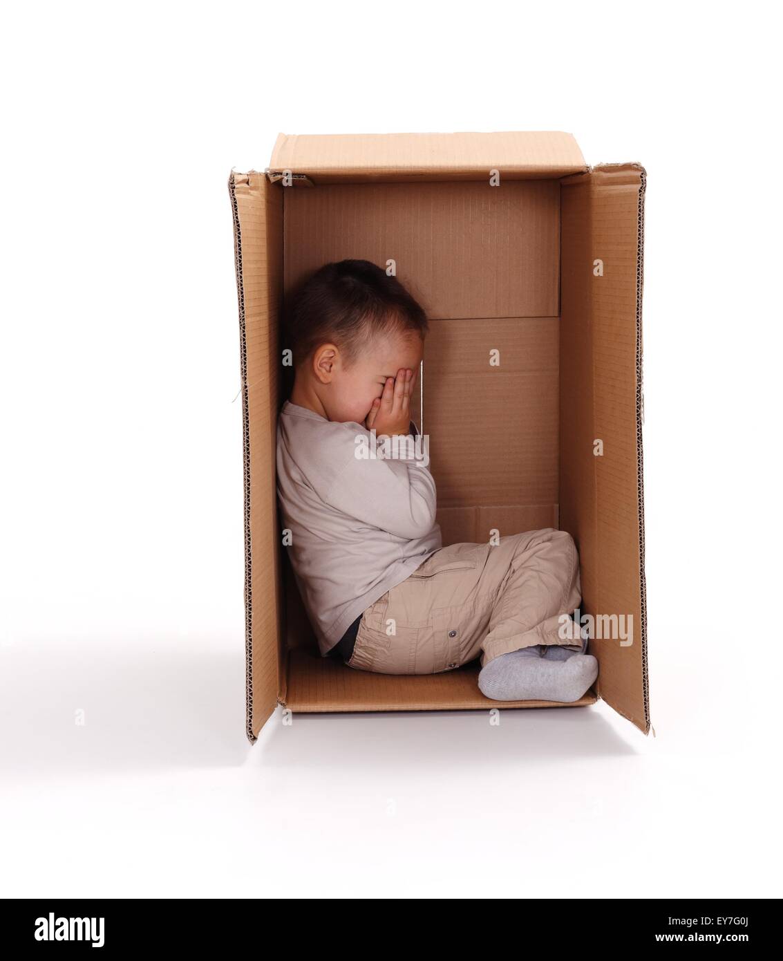 Little boy sitting in cardboard box, hiding his face with hands Stock ...