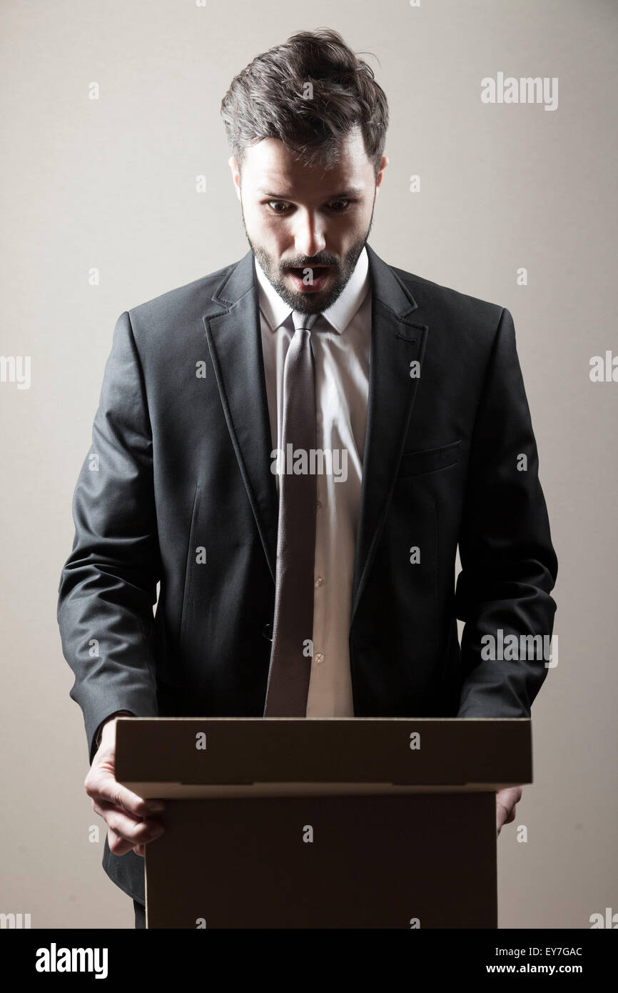 Businessman looking at cardboard box mouth open Stock Photo - Alamy