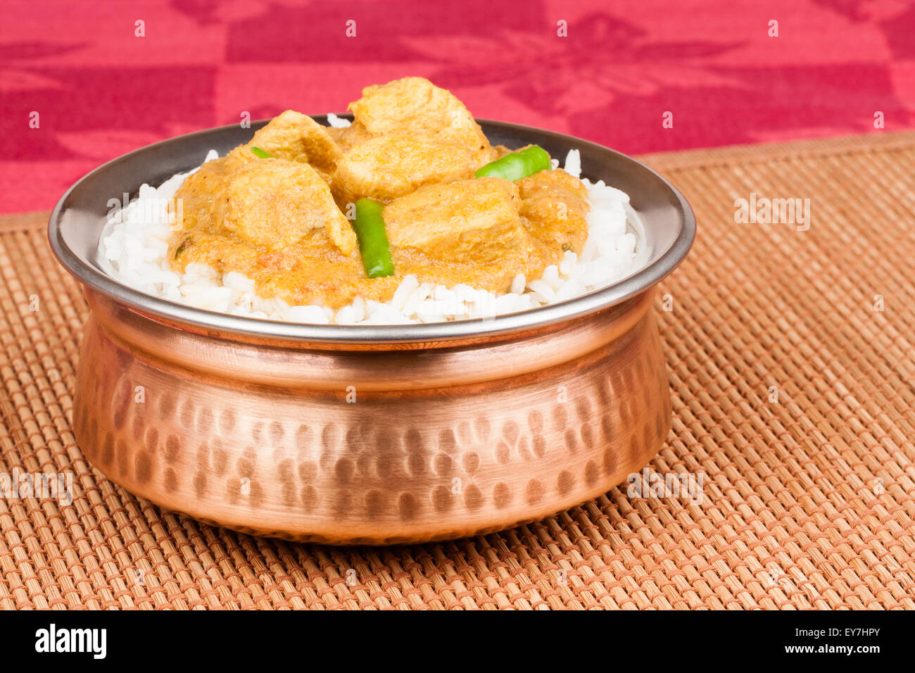 Indian chicken curry served on rice in authentic copper bowl. Green ...