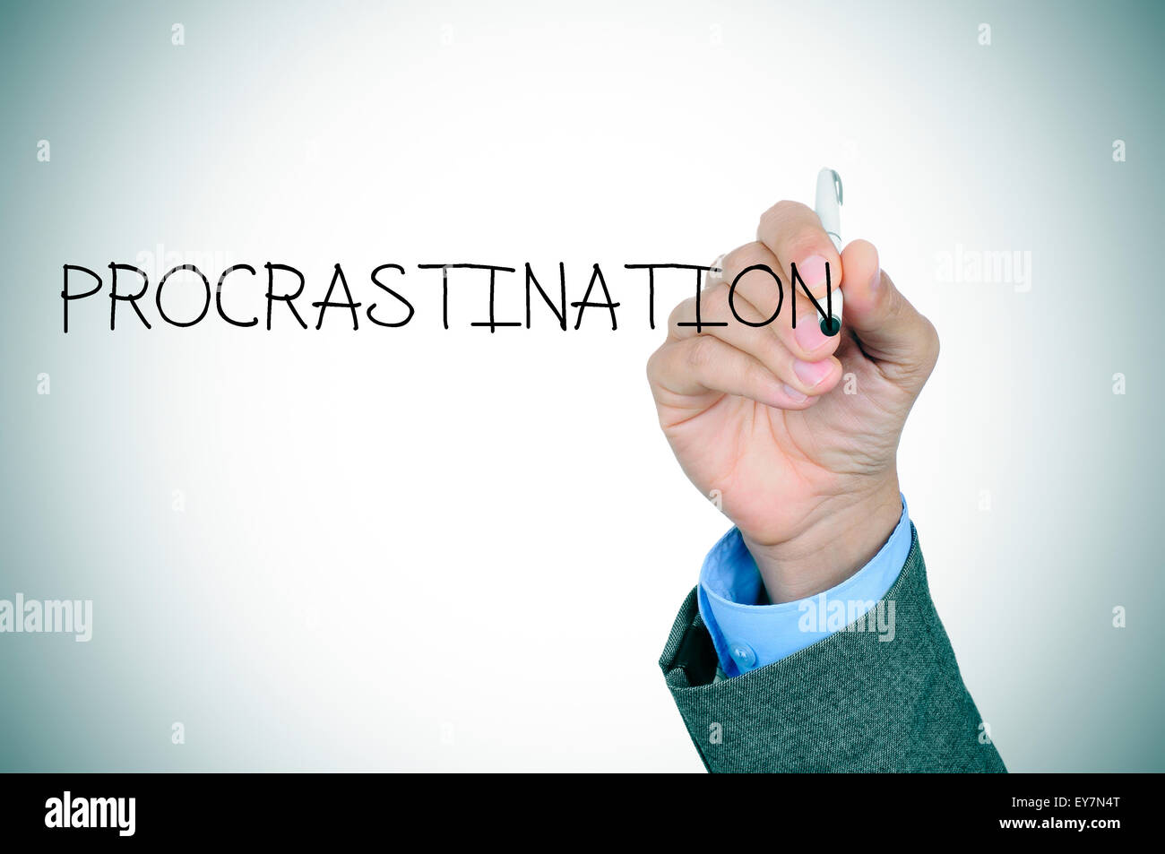 closeup of the hand of a man writing the word procrastination in the ...