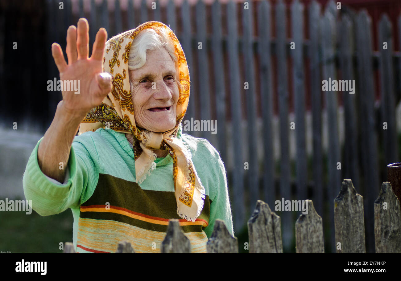 Old woman romanian countryside Elderly woman waves cheerfully from her ...