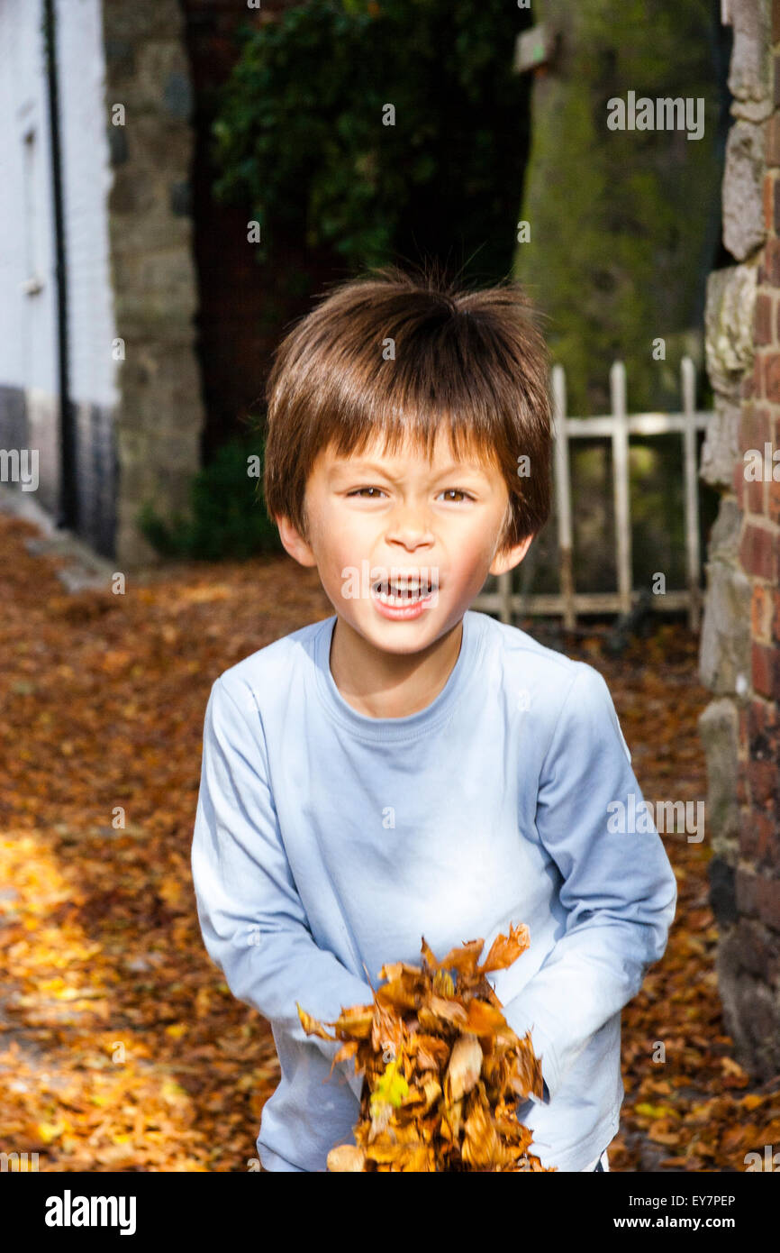 Caucasian child, boy, 6-7 year old, standing in leave covered road ...