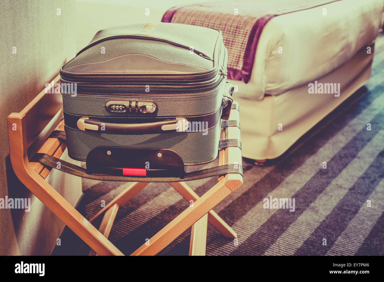 Hotel room with a suitcase on the luggage place and the bed. Filtered ...
