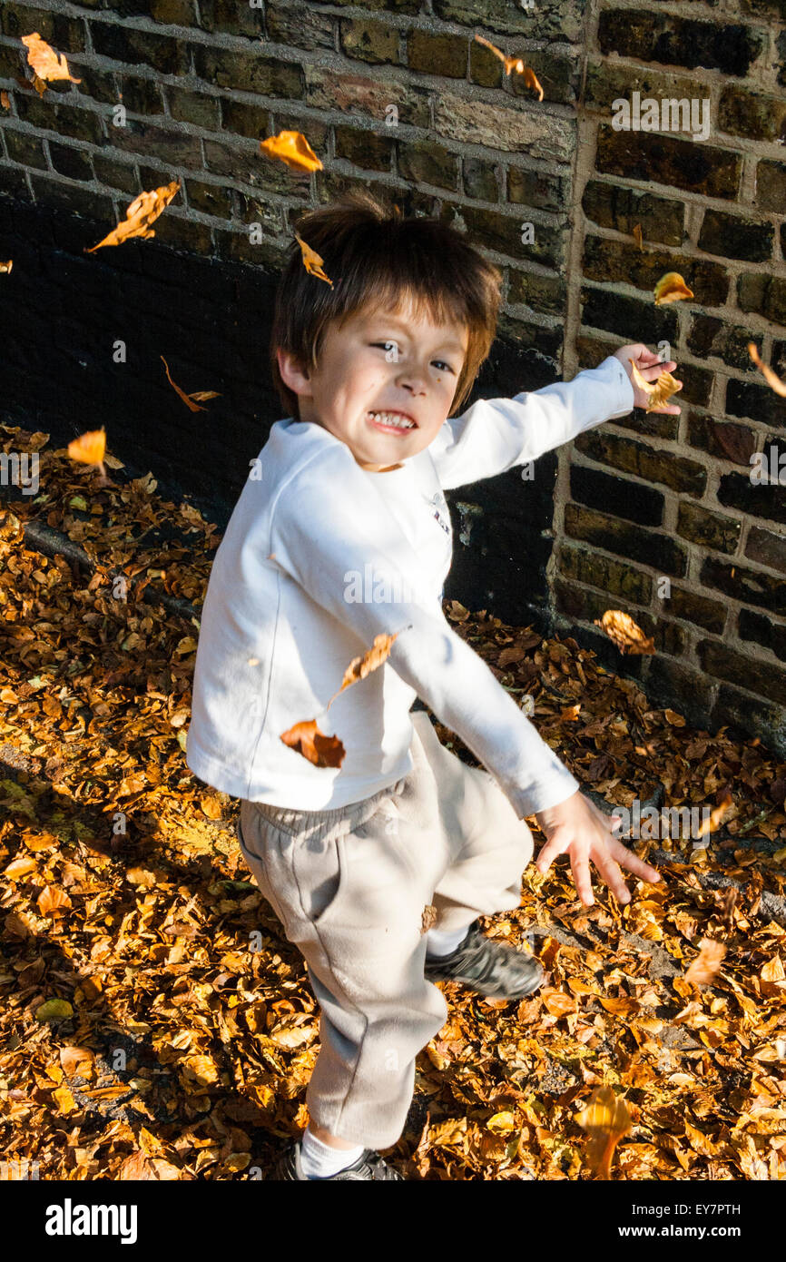 Caucasian child, boy, 5-6 year old, throwing handfuls of leaves at ...