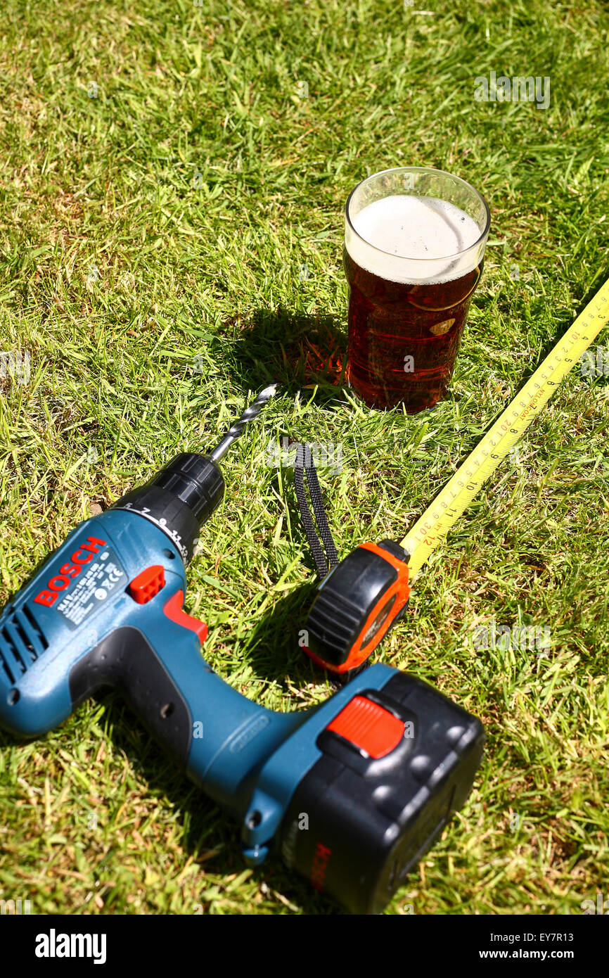 Work tools laid on the grass with a pint of bitter in the summer Stock ...