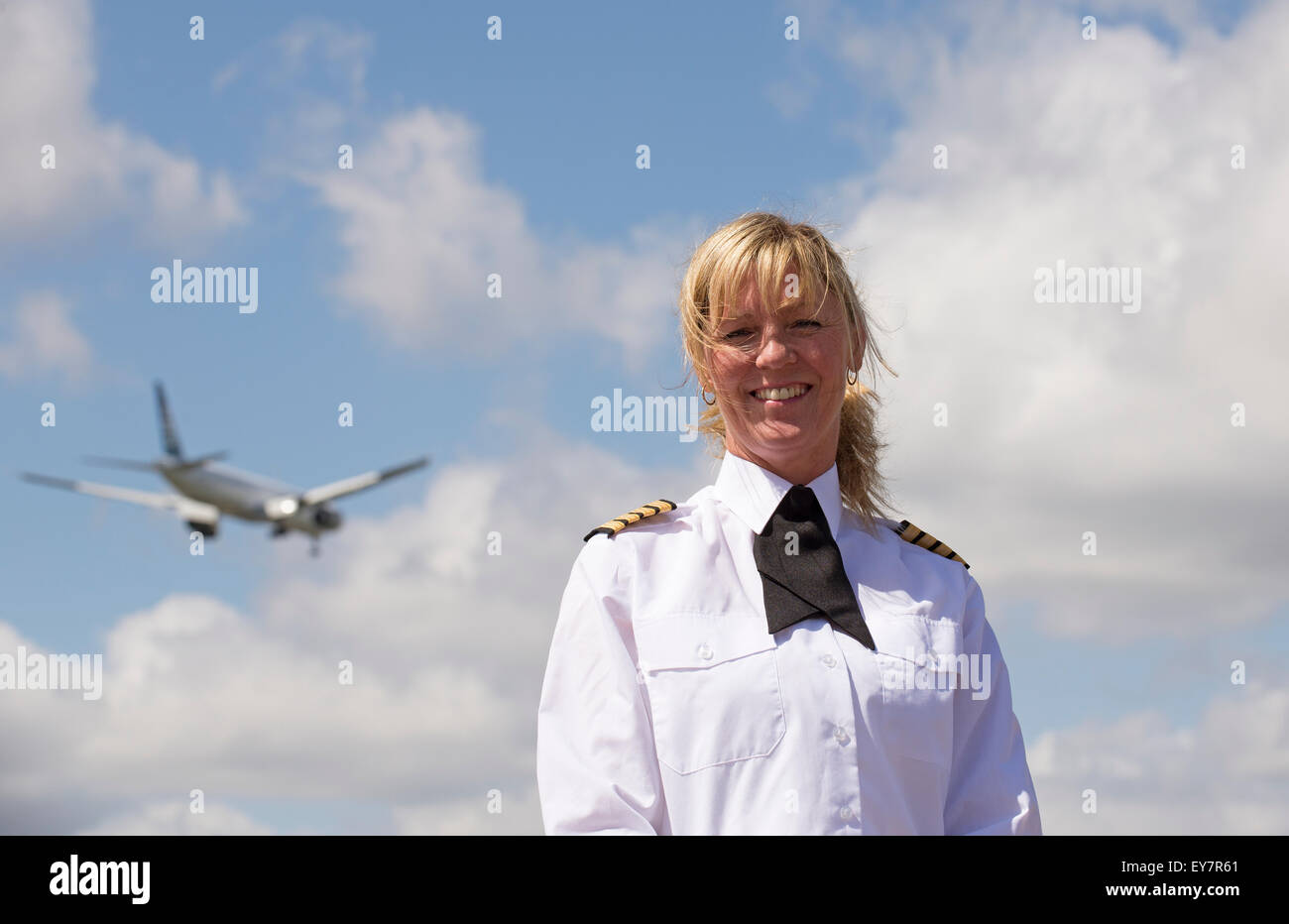 Portrait of a woman pilot with a passenger jet in the sky Stock Photo ...