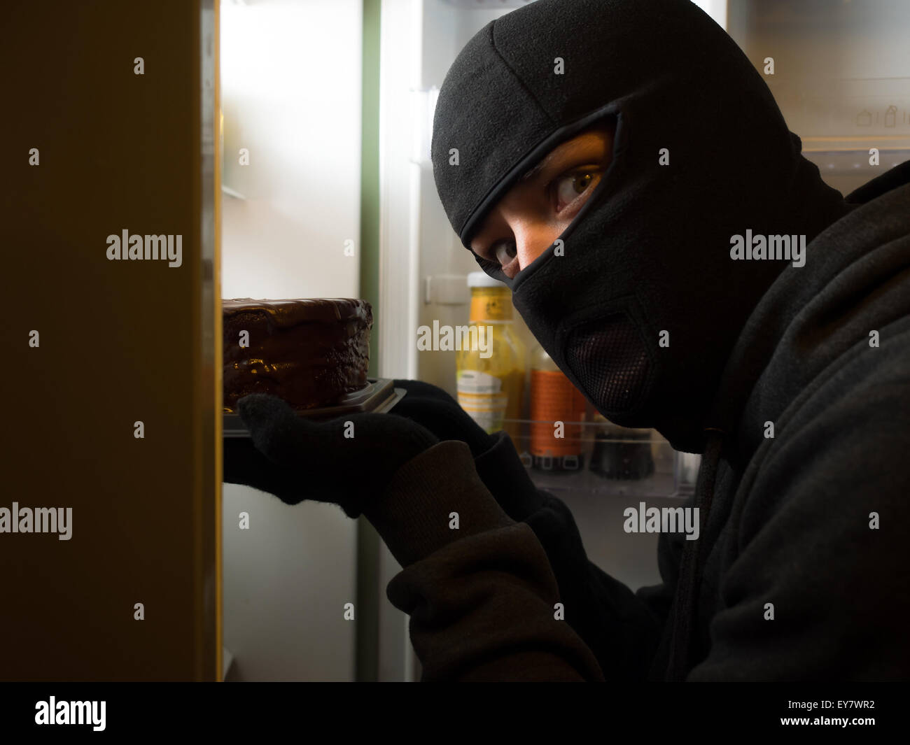 Thief. Man in black mask with a cake Stock Photo - Alamy