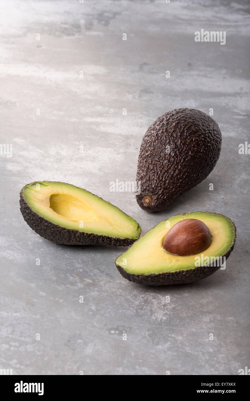 A Half and a whole Avocado on rustic metal background Stock Photo - Alamy