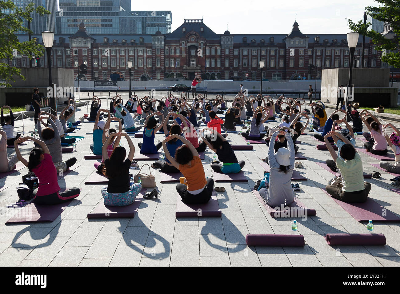 Office workers practice yoga early morning in front of Tokyo Station ...