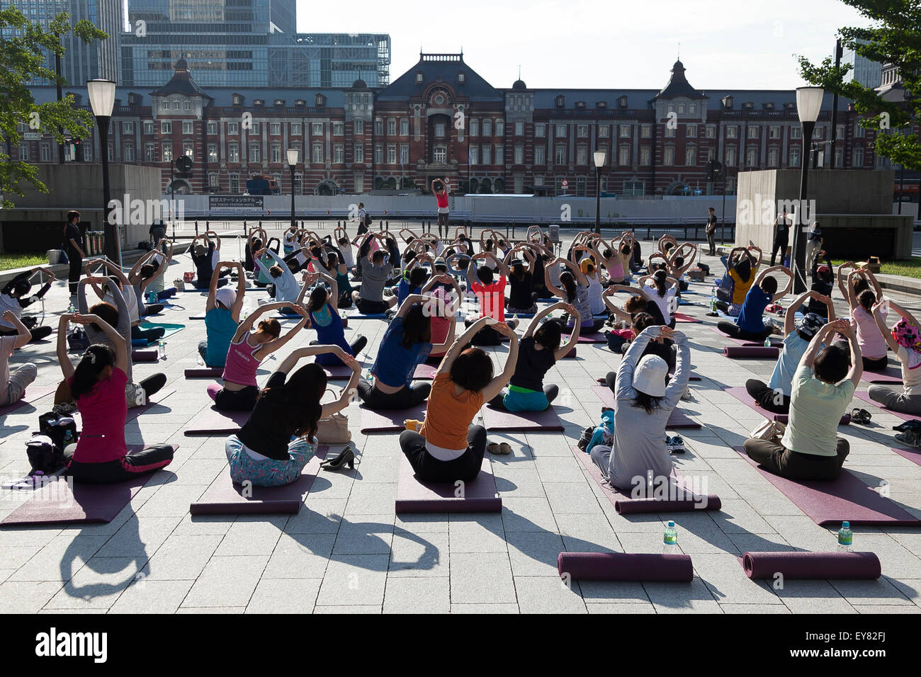 Office workers practice yoga early morning in front of Tokyo Station ...