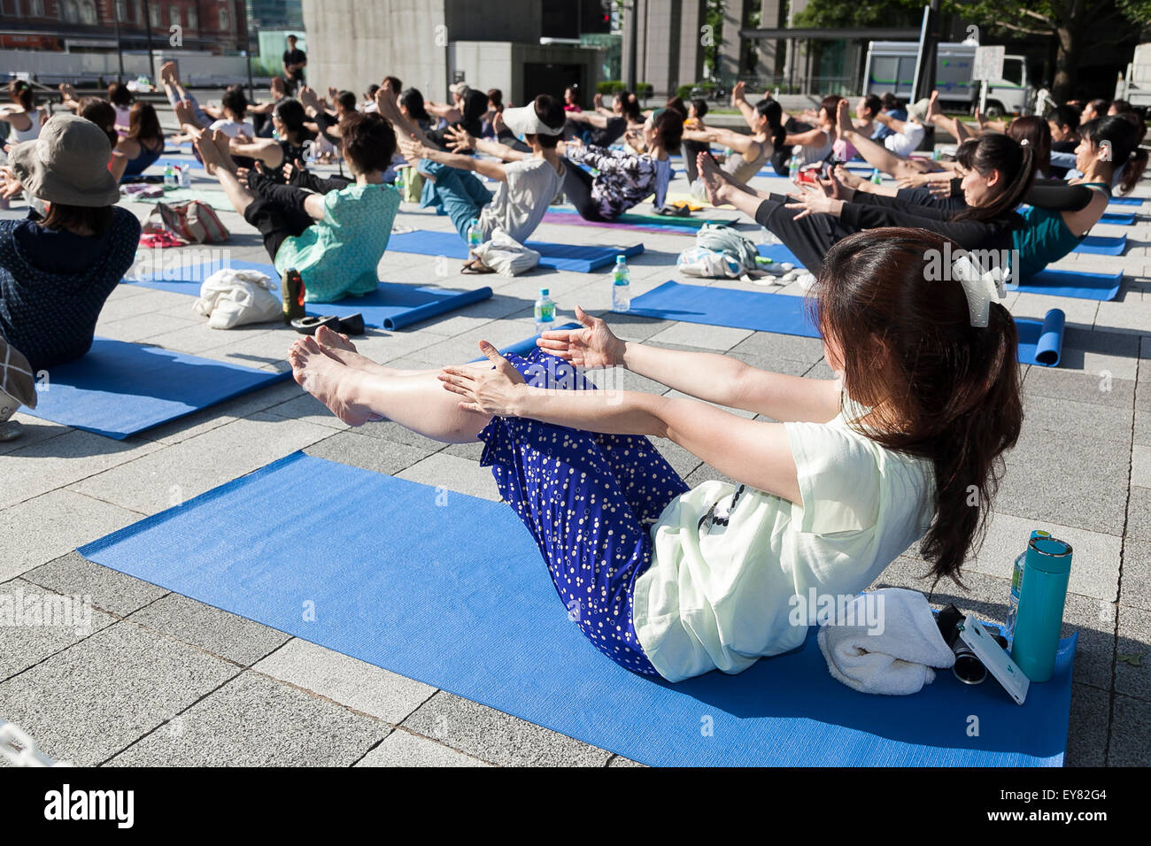 Office workers practice yoga early morning in front of Tokyo Station ...