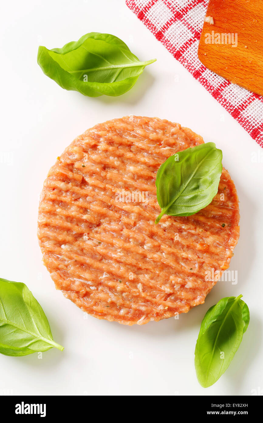 Raw burger patty with fresh basil leaves Stock Photo - Alamy