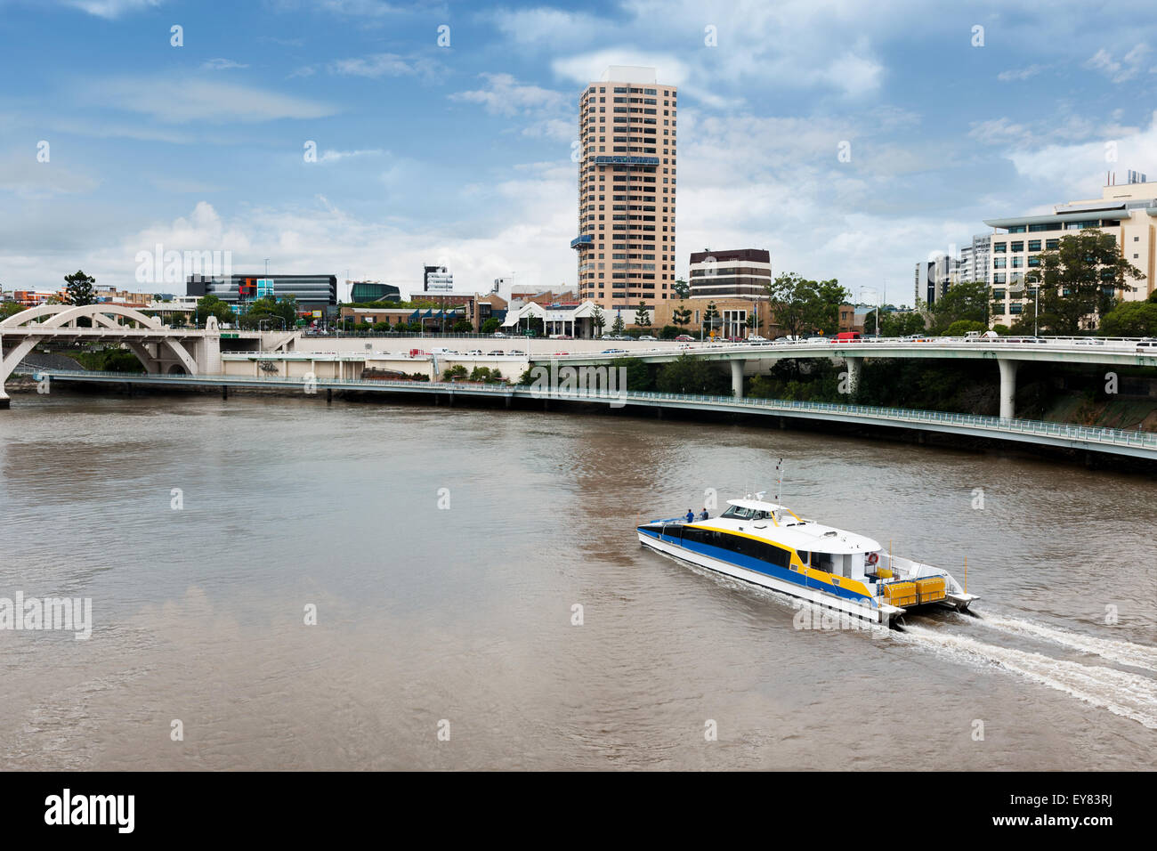 A stylish vessel moves on Brisbane River with modern buildings on the ...