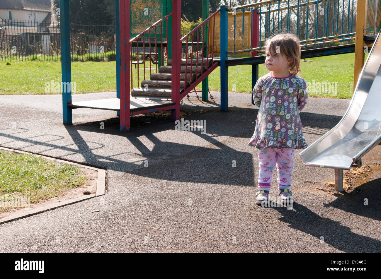Toddler standing alone in the playground looking wistful Stock Photo ...